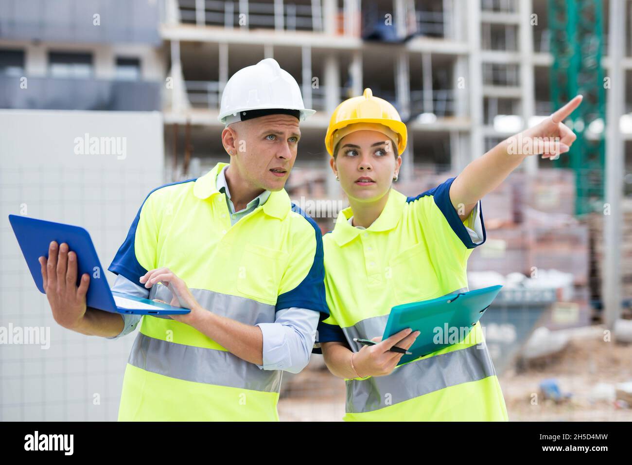 Male and female european builders talking about their work while ...