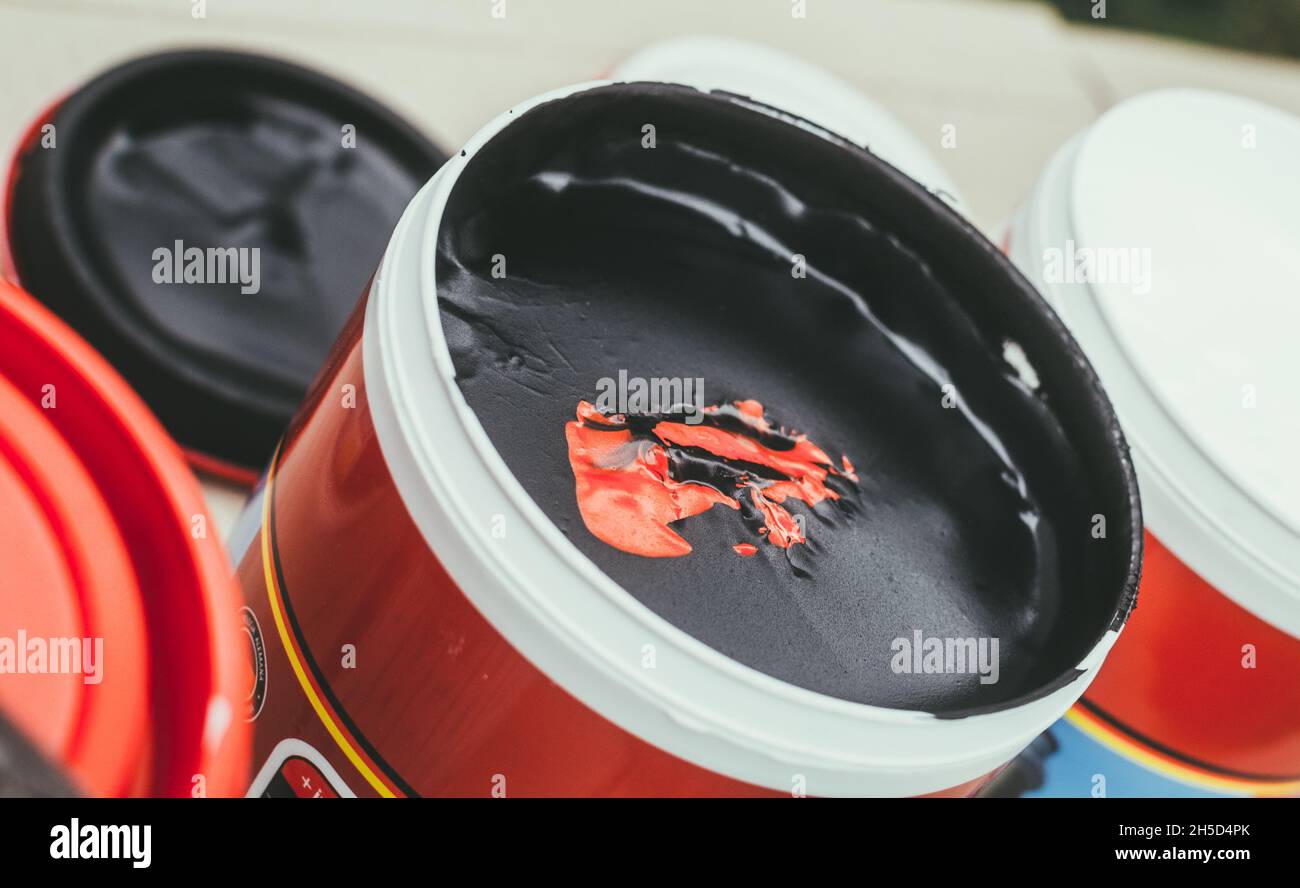 Container with black paint and a little red paint Stock Photo - Alamy