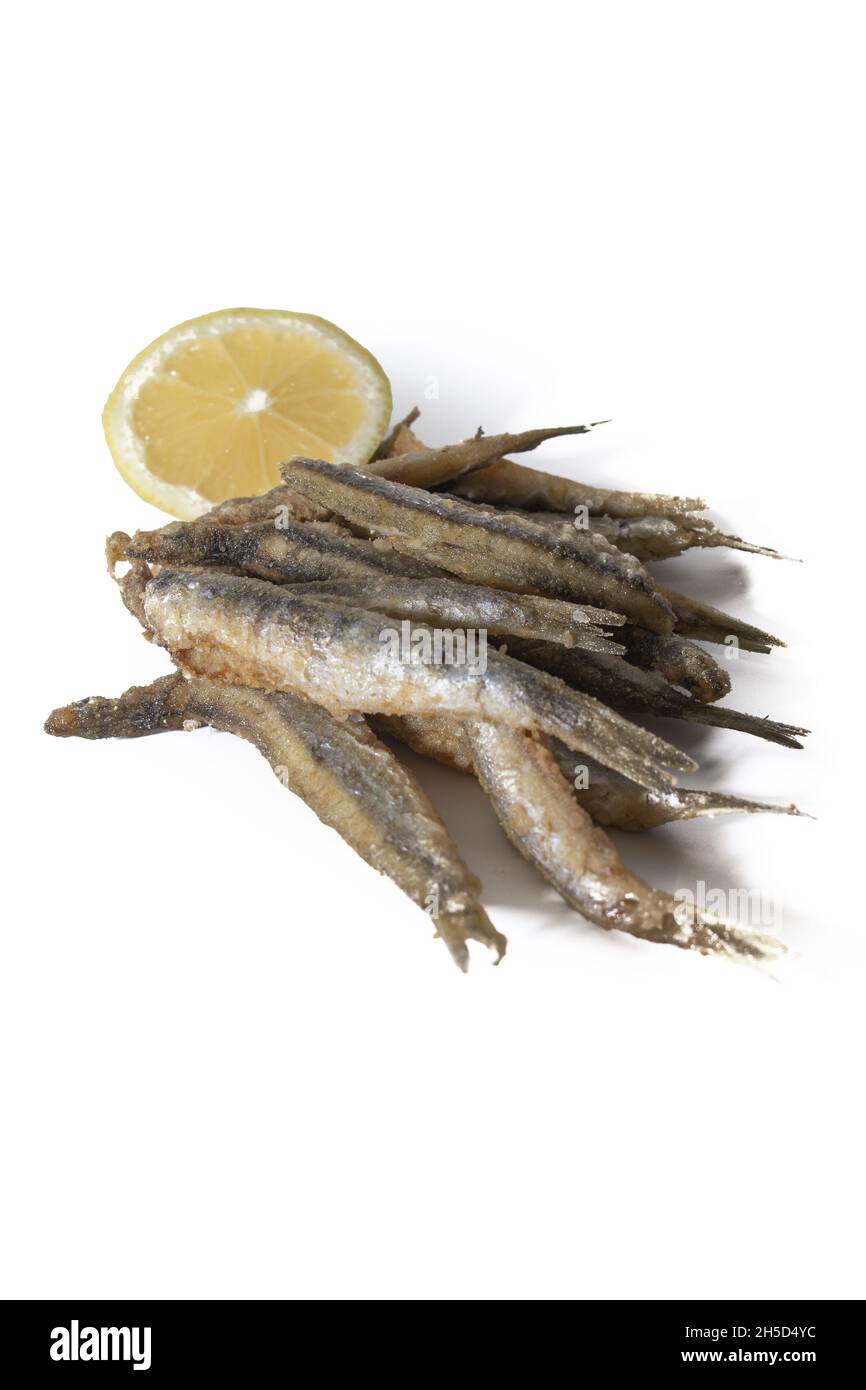Closeup of fried anchovies with a lemon slice isolated on white ...