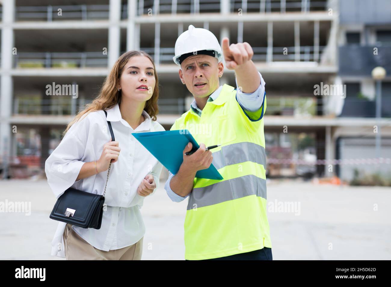 Builder talking with client at construction site Stock Photo - Alamy