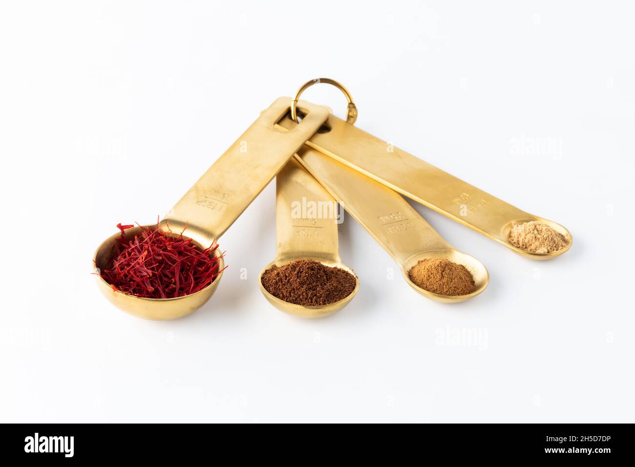 Measuring spoons filled with various spices against a white background ...