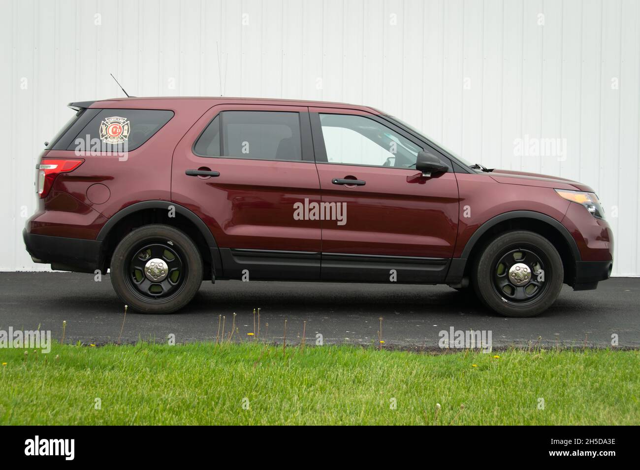 Maroon car parked along a street against a white wall building Stock ...