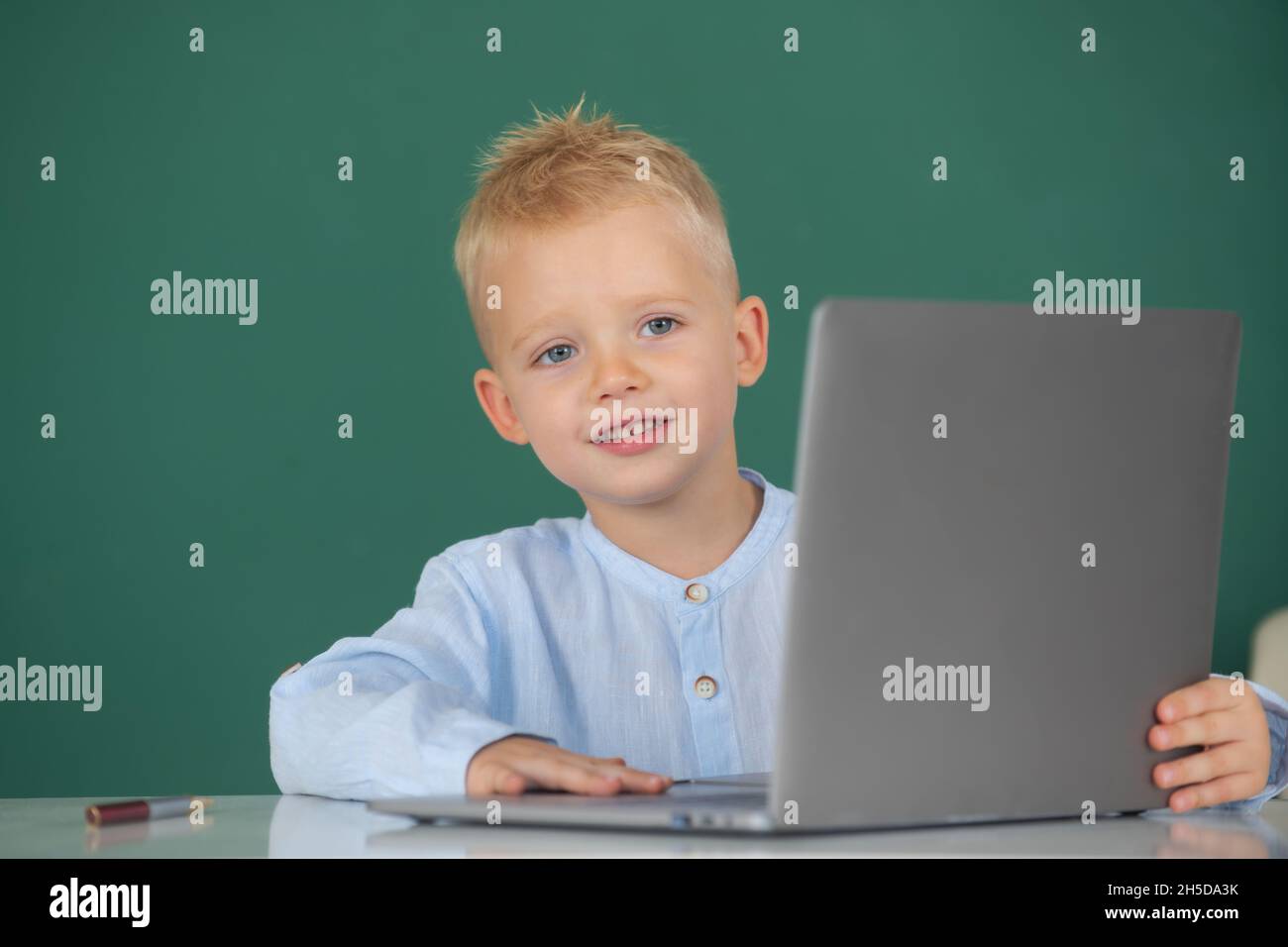Child boy using a laptop computer at school. Cute pupil face closeup on ...