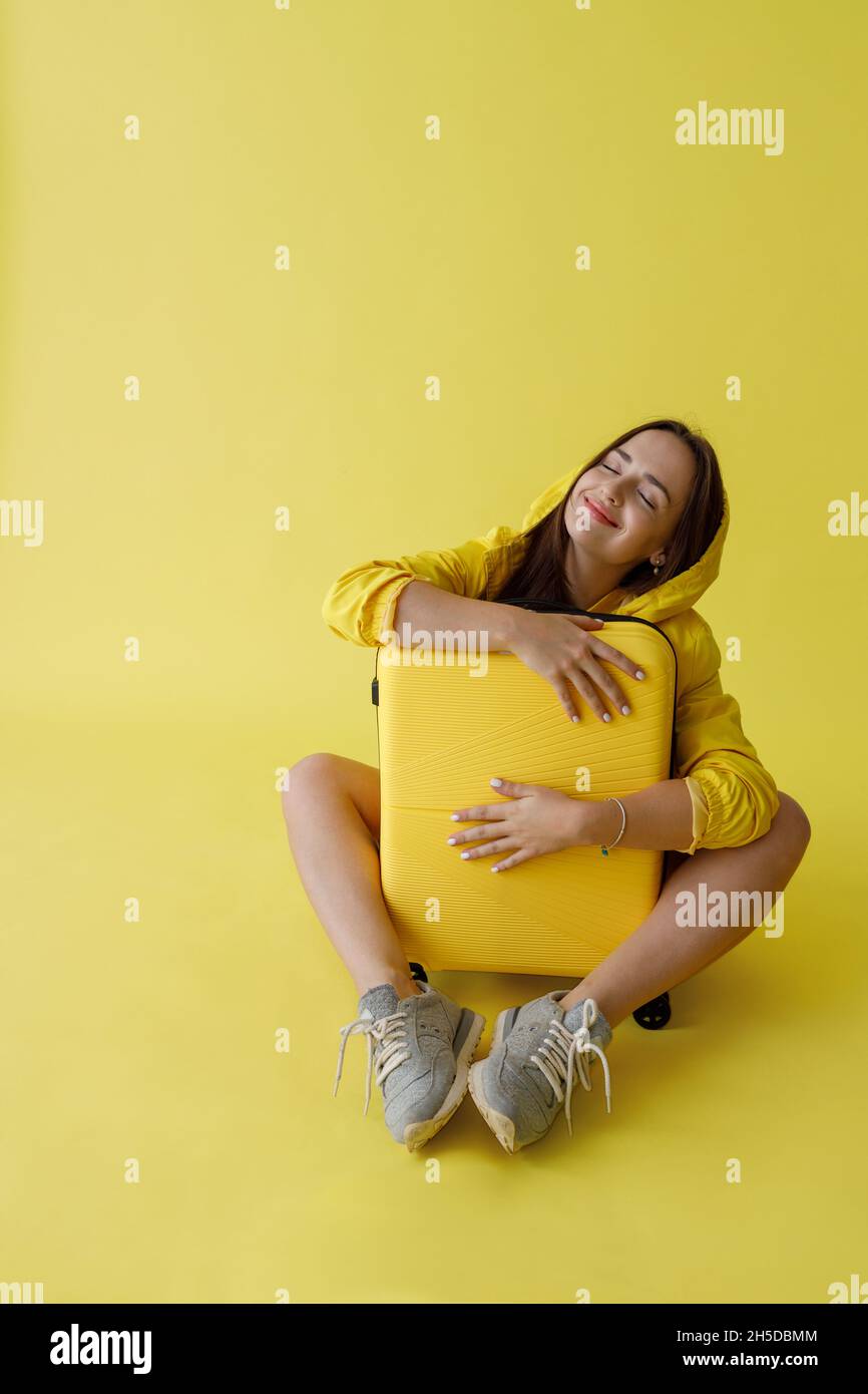 Cheerful young woman hugging travel bag in studio Stock Photo - Alamy