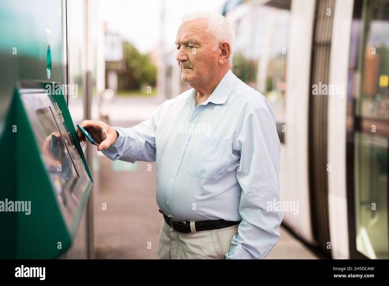 Old man using cash machine with smartphone Stock Photo - Alamy