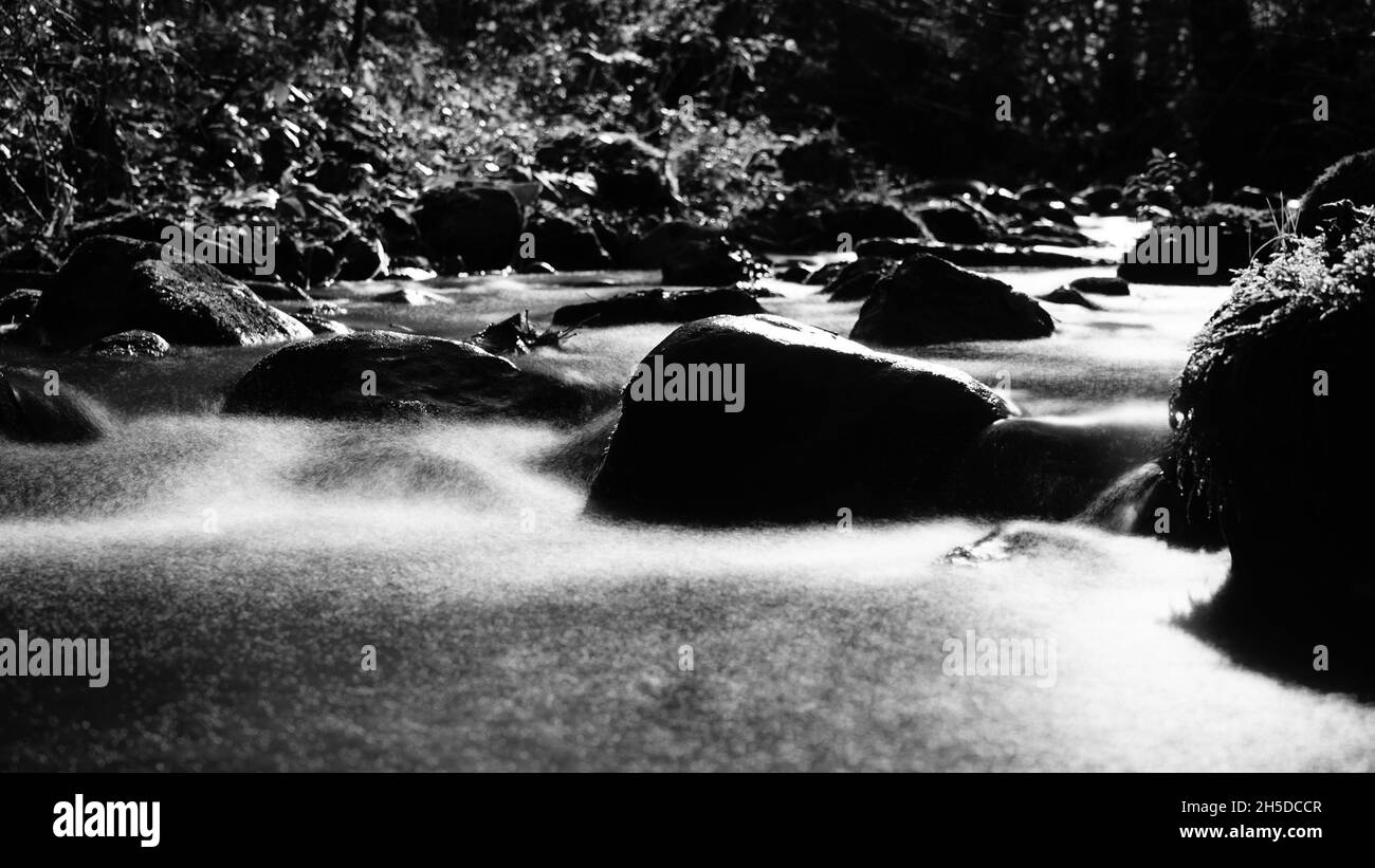 Grayscale shot of flowing river over rocks with long exposure Stock ...
