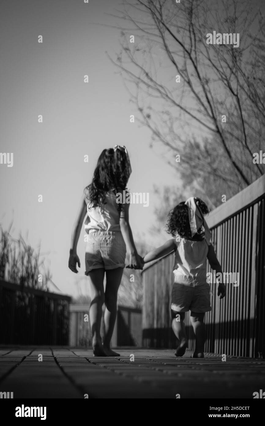 Rear view of young twinning girls walking on a park in grayscale Stock ...
