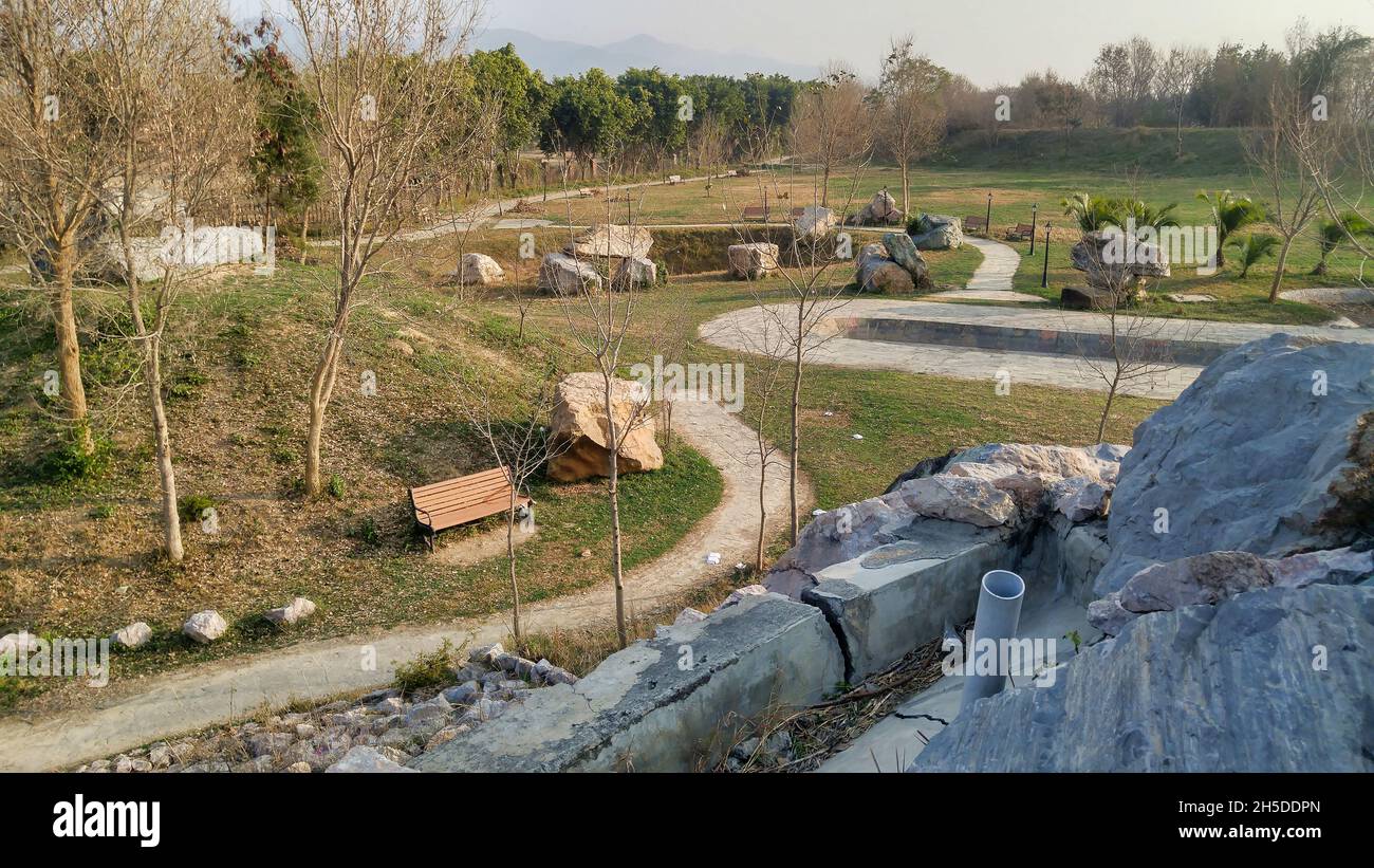 Natural view of a walking path pavement in a park covered in greenery ...