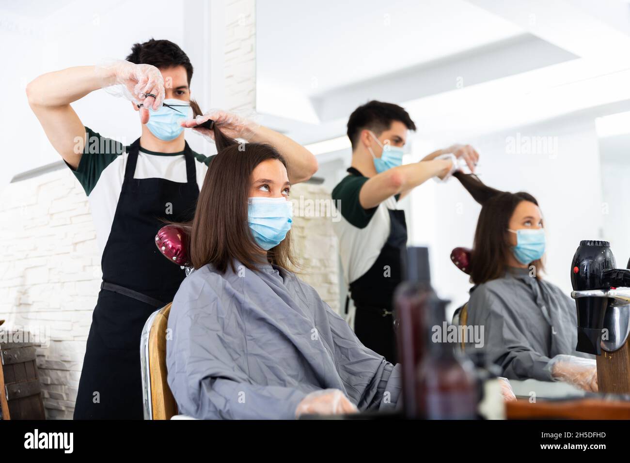 Man doing haircut for woman in salon using face masks Stock Photo - Alamy