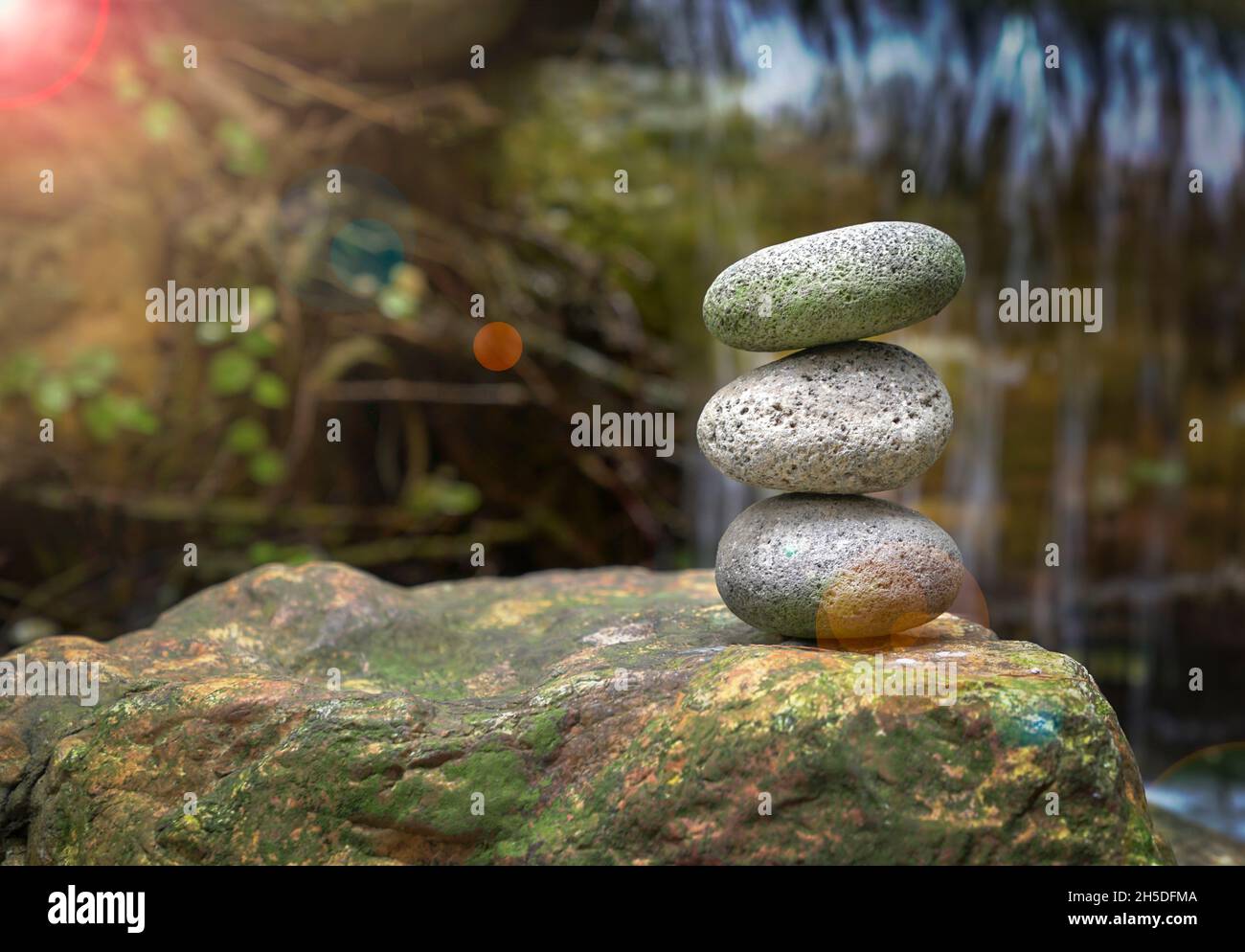Stacked stones with waterfall at the background and lens flare Stock ...
