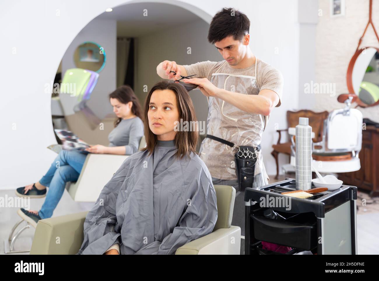 Nice hairdresser and client getting haircut Stock Photo - Alamy
