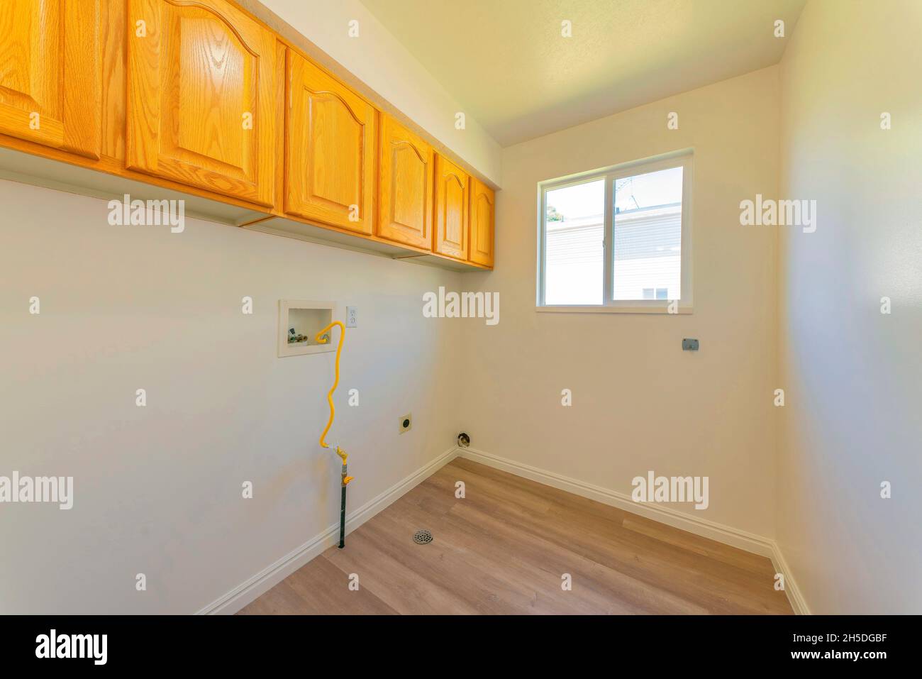 Empty laundry room with wooden wall cabinets and window Stock Photo - Alamy