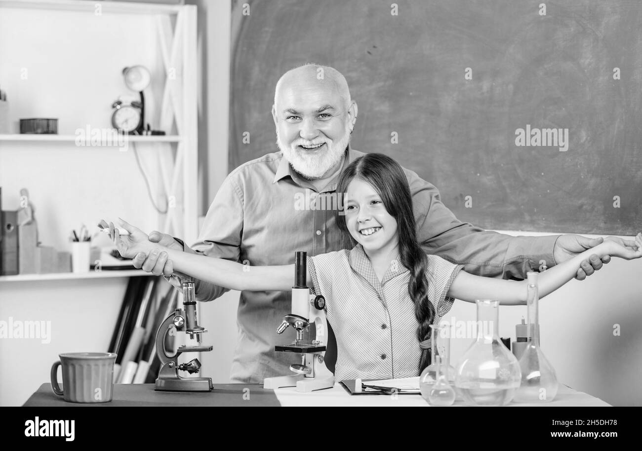 Teacher help schoolgirl. Little girl with man tutor study science ...