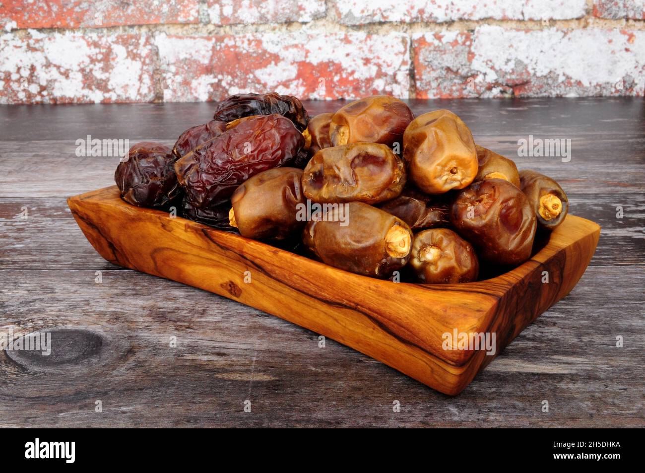 Group of ripe soft and sticky medjool and zamli dates in an olive wood ...