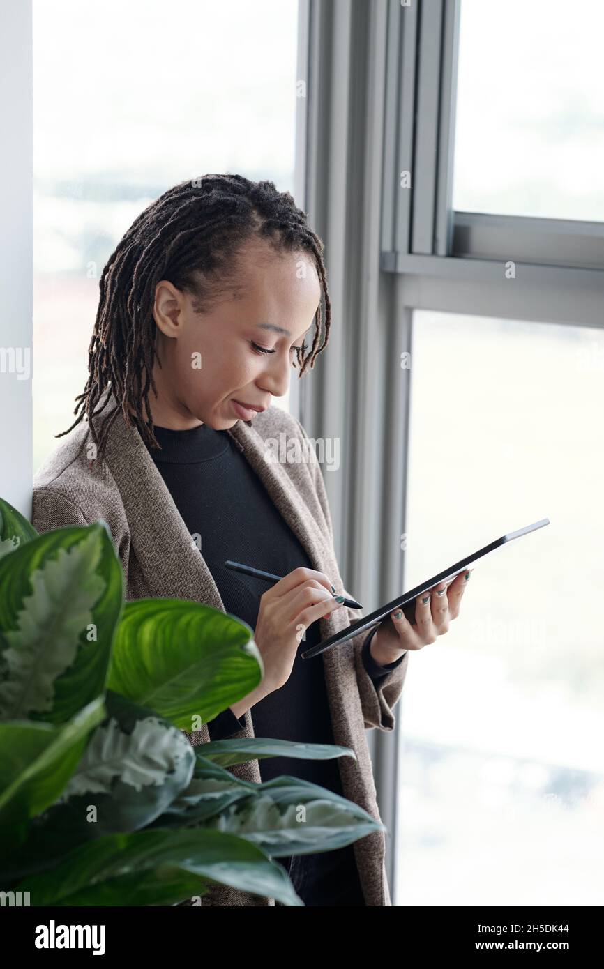 Successful Black female entrepreneur signing documents on tabet ...
