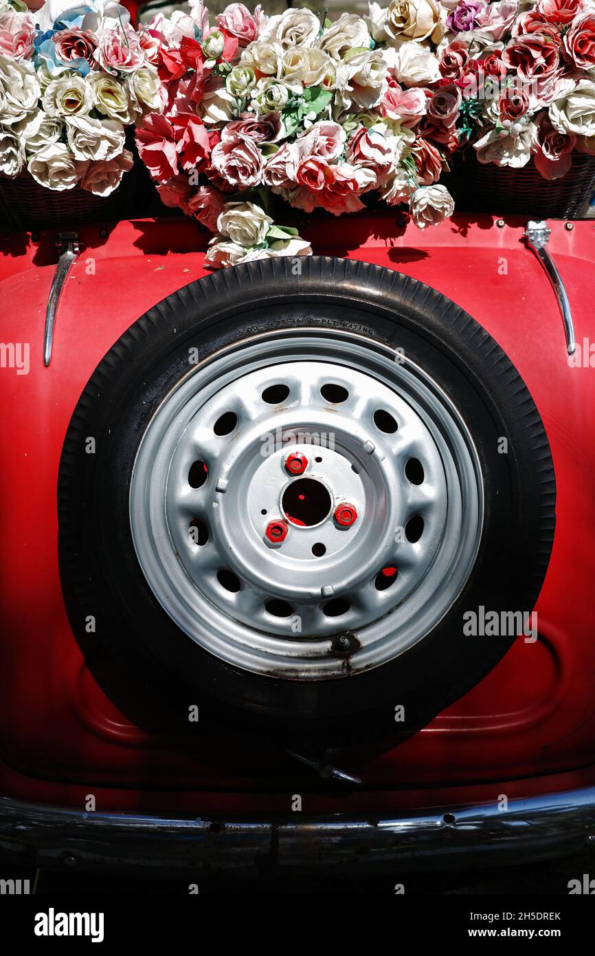 Classic old style of unuse red car and hanging black tire wheel on back ...