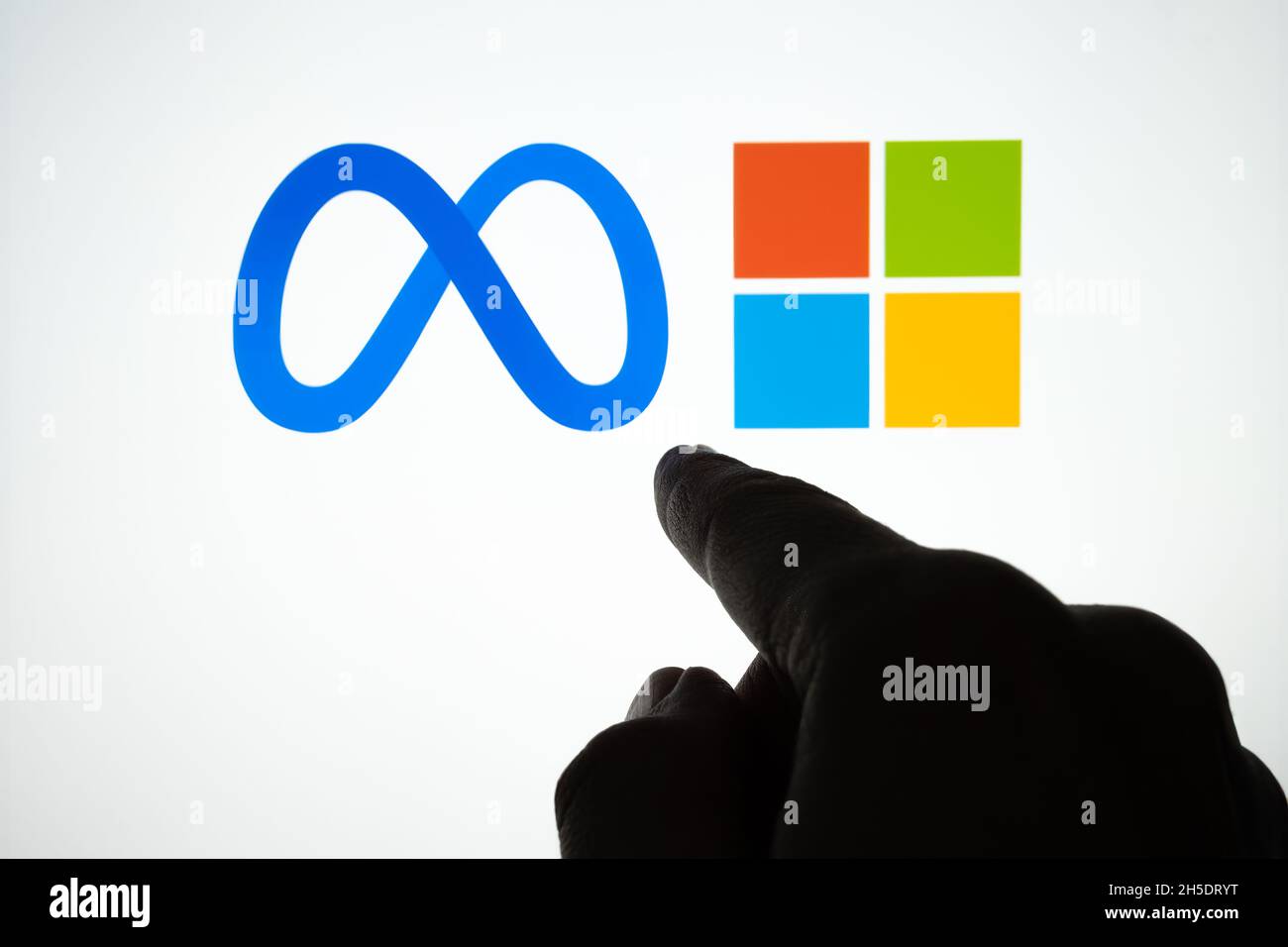 Silhouette of hand pointing at blurred FACEBOOK META and MICROSOFT ...