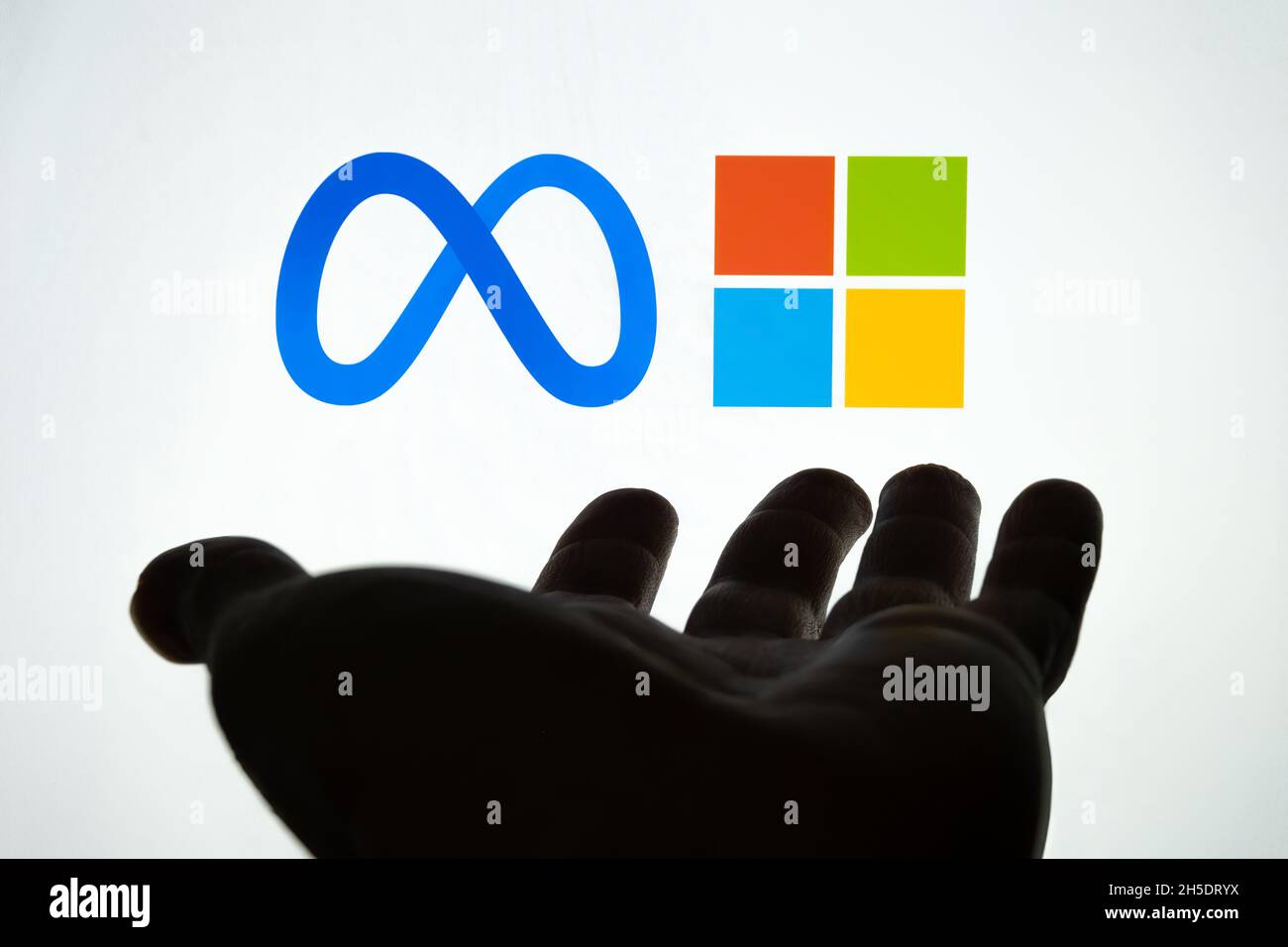 Silhouette of hand pointing at blurred FACEBOOK META and MICROSOFT ...