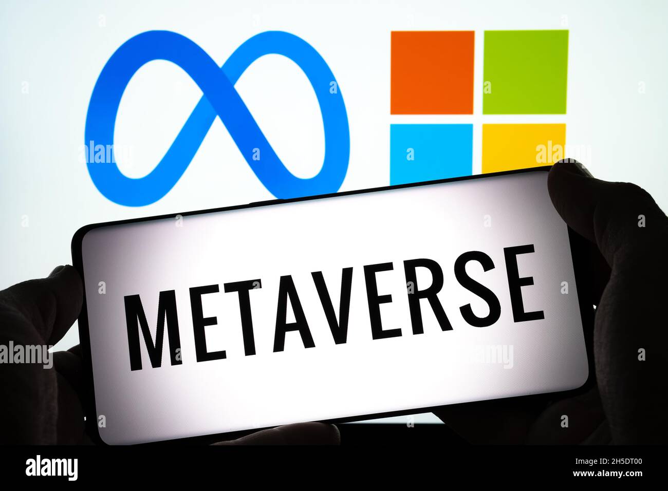 Silhouette of smartphone with METAVERSE word hold in hand and blurred ...