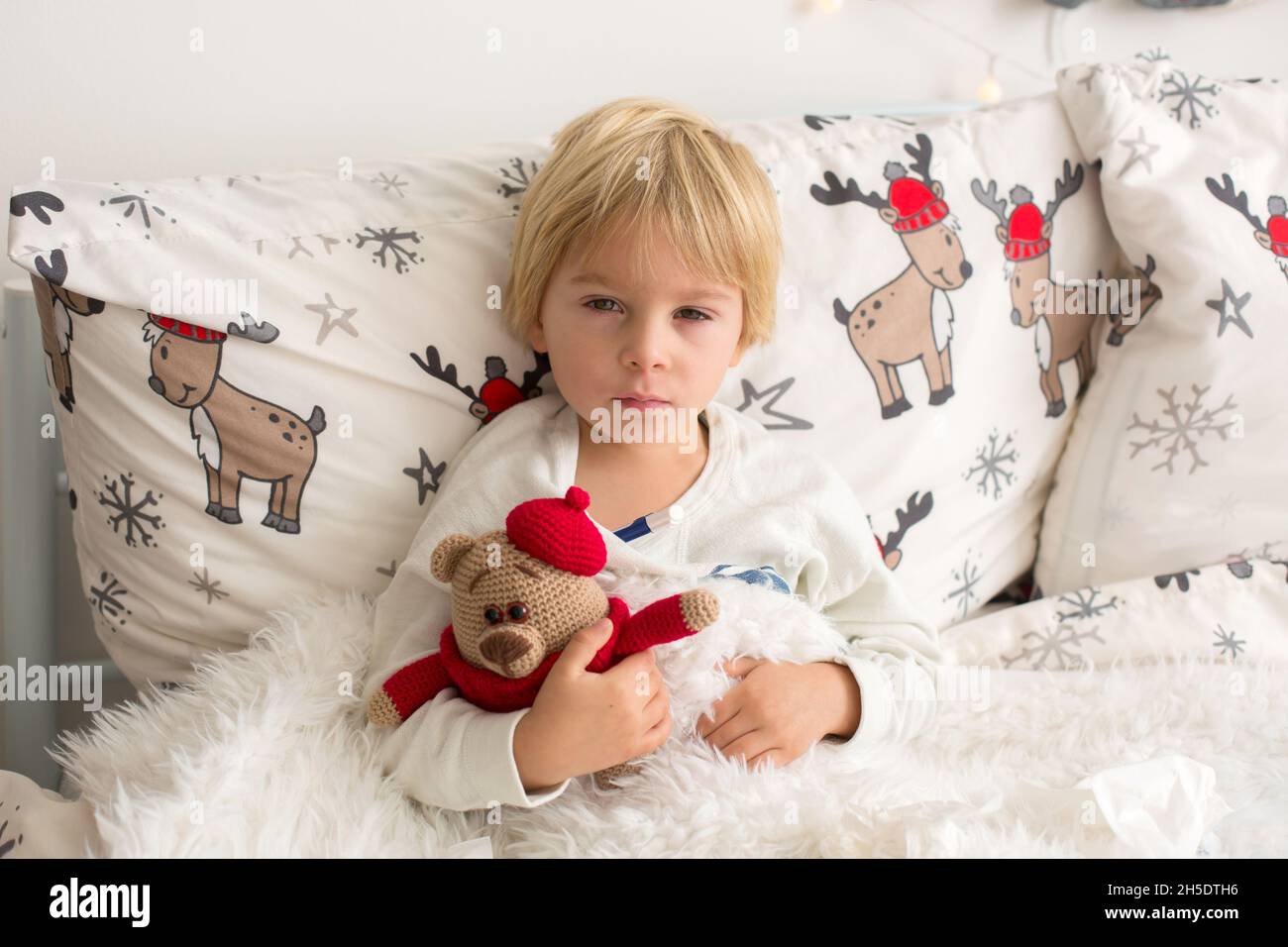 Beautiful blond toddler child, sick boy with fever, lying in bed on ...