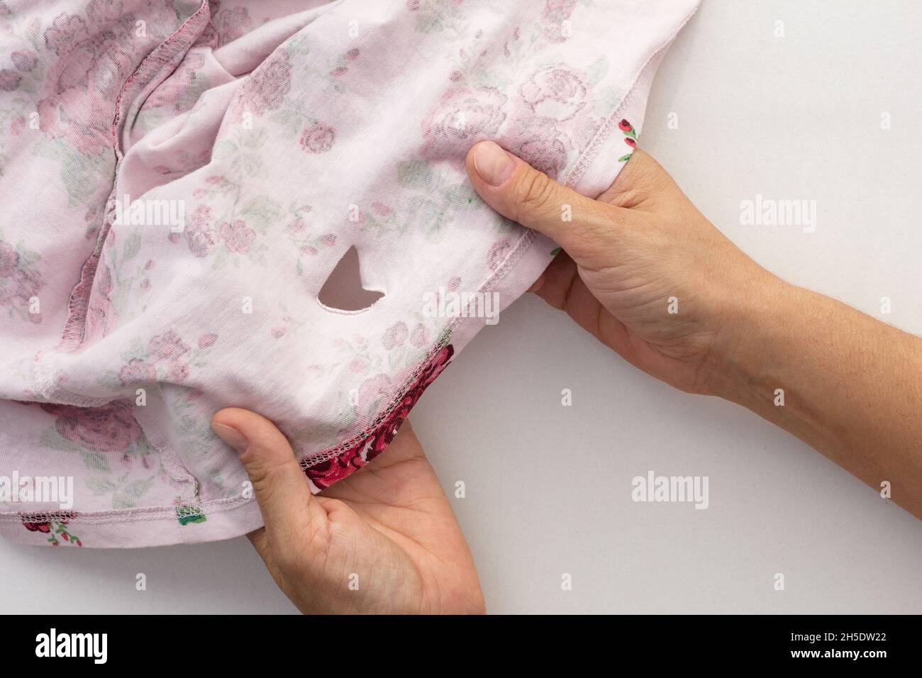 Woman hand holding torn cloth seamy side showing hole on white ...