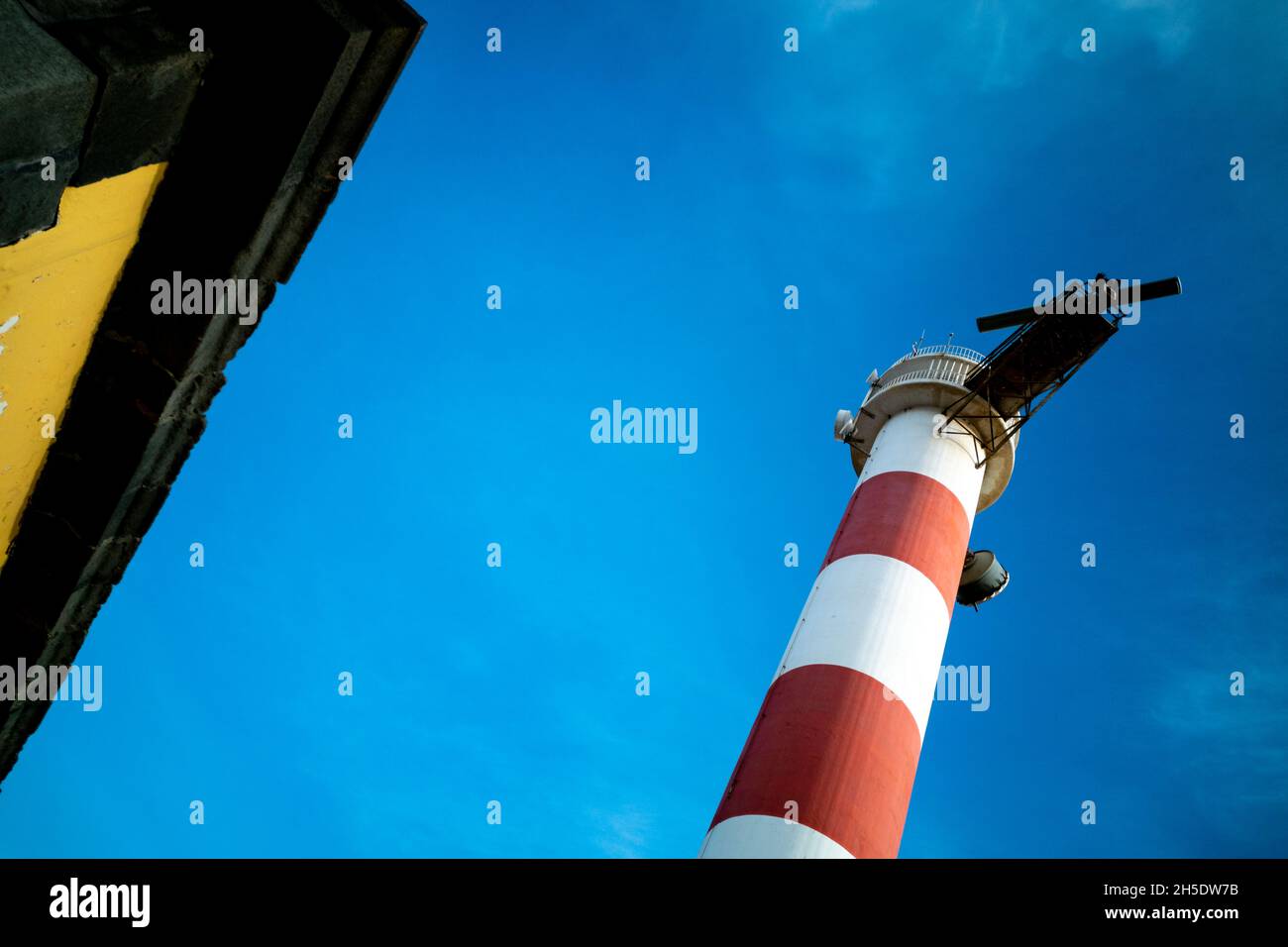 Low angle shot of a red and white striped lighthouse against the blue ...