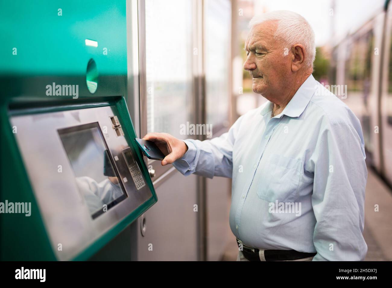 Old man using cash machine with smartphone Stock Photo - Alamy