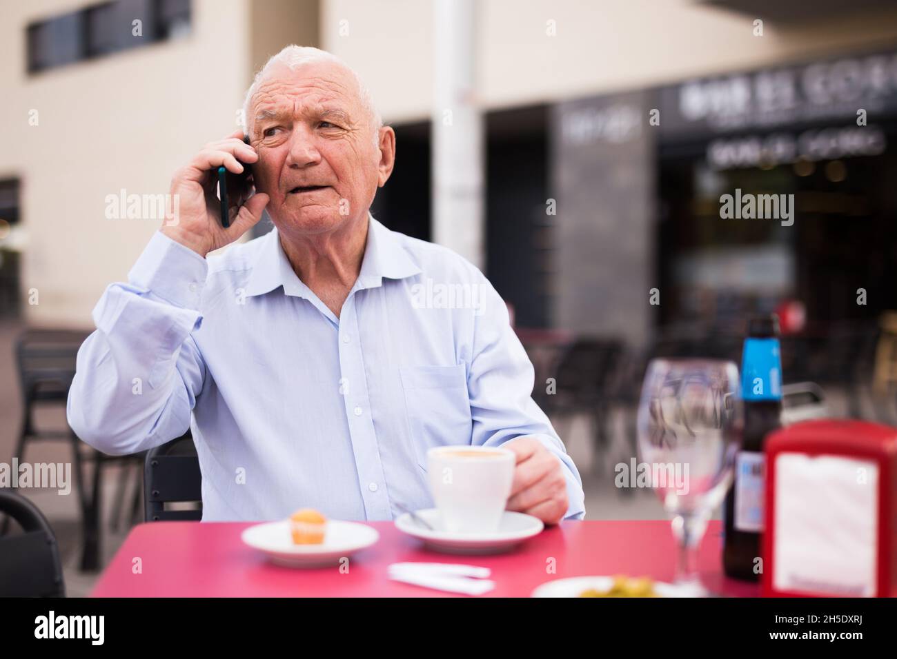 Old man having telephone conversation in outdoor cafe Stock Photo - Alamy