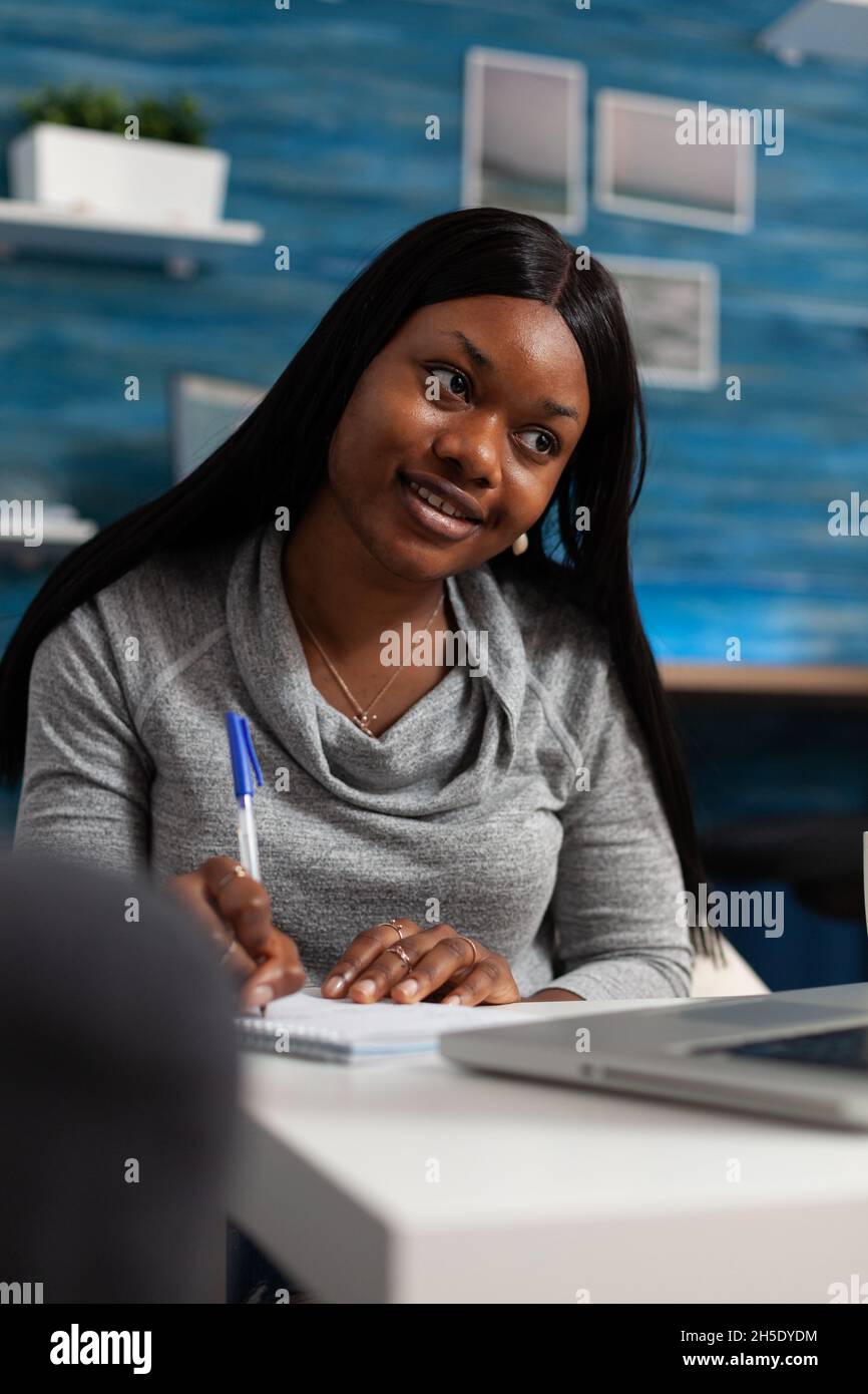 African american woman writing information on textbook file with pen ...