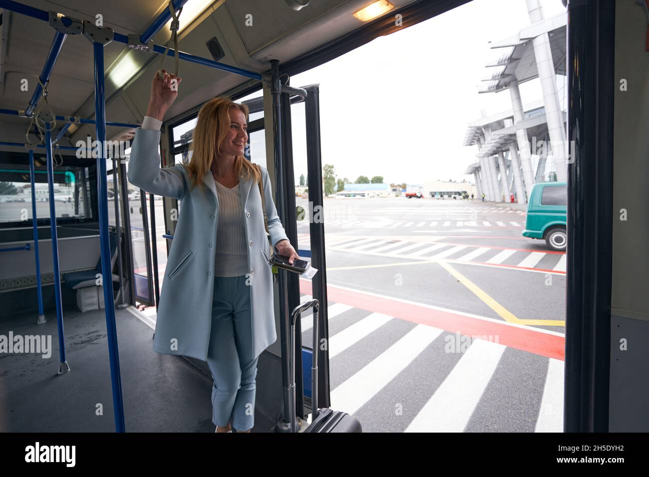 Straphanger with boarding ticket and baggage riding airport shuttle bus ...