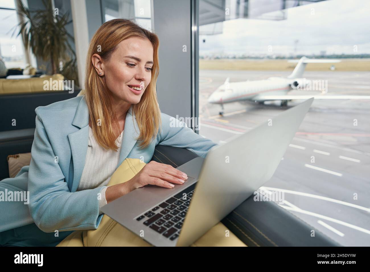 Traveler using her notebook computer in airport lounge Stock Photo - Alamy