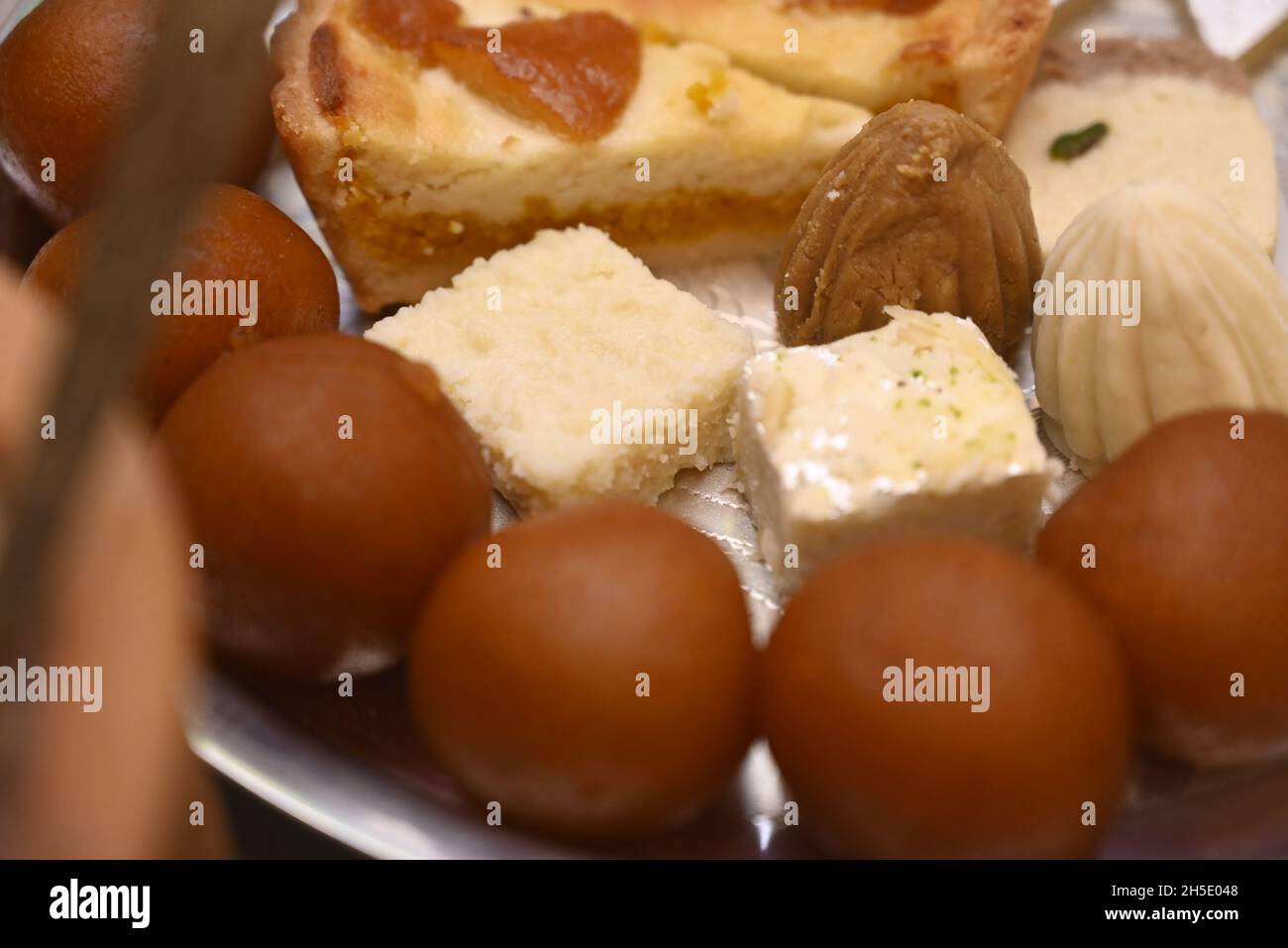 Indian sweets in a plate includes Gulab Jamun, Rasgulla, kaju katli ...