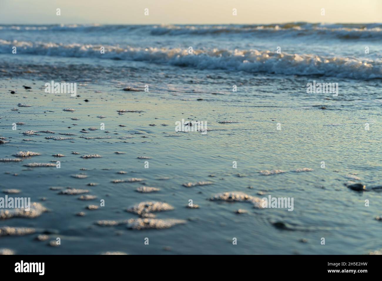 Waves roll onto the beach shore at sea before sunset. Beautiful nature ...