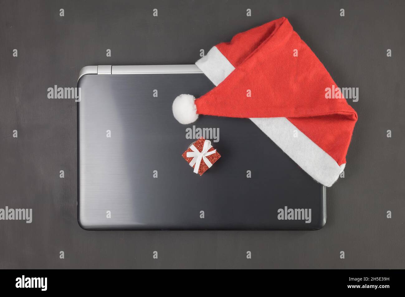 A red santa claus hat is worn on the corner of a laptop with a red ...
