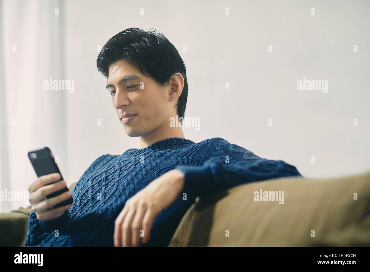 Japanese man relaxing on the sofa Stock Photo - Alamy