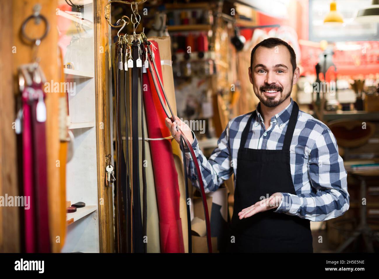 man worker displaying various belts in leather workshop Stock Photo - Alamy