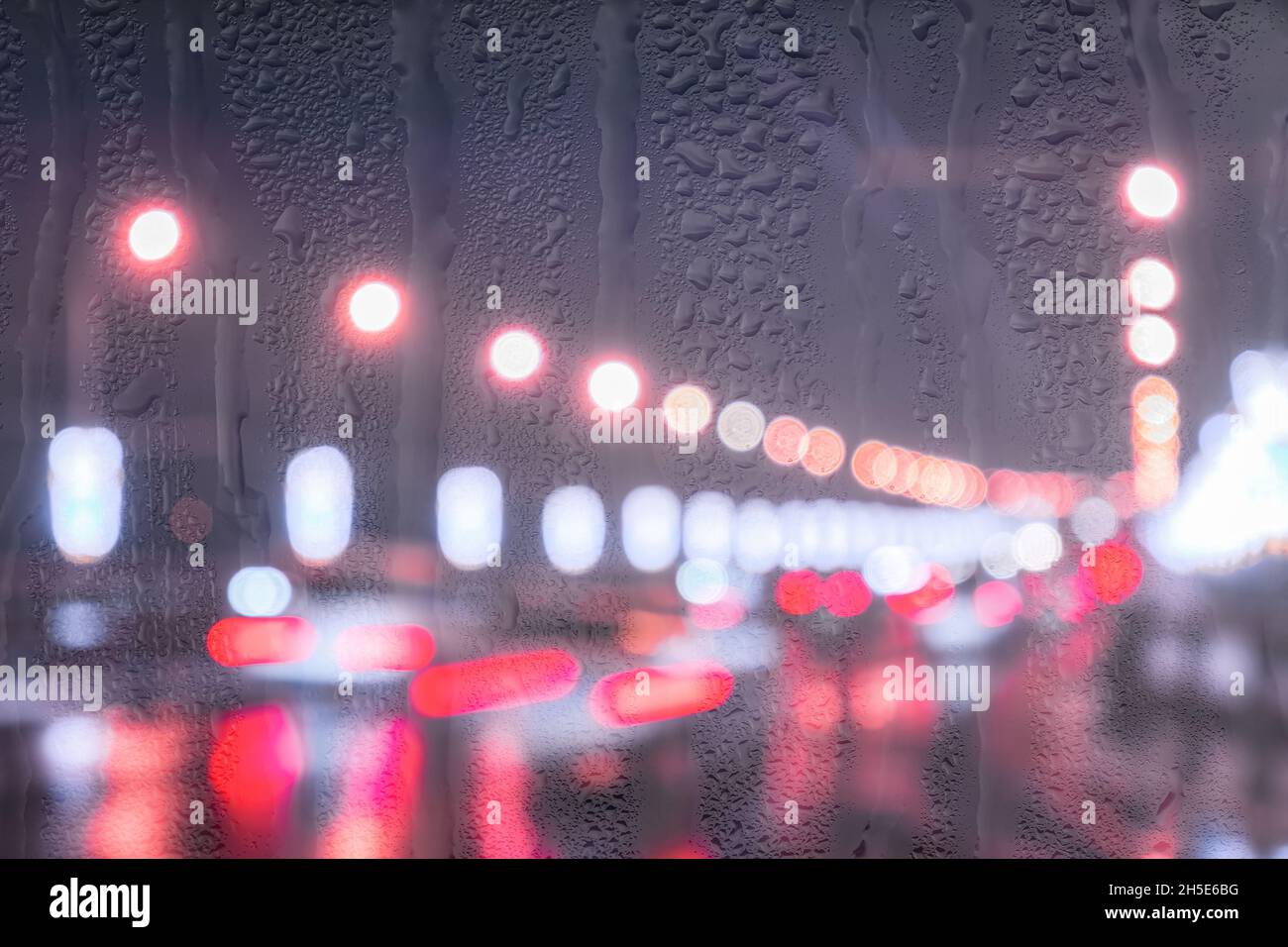 Blurry lights of moving cars and lanterns reflecting on the wet asphalt ...