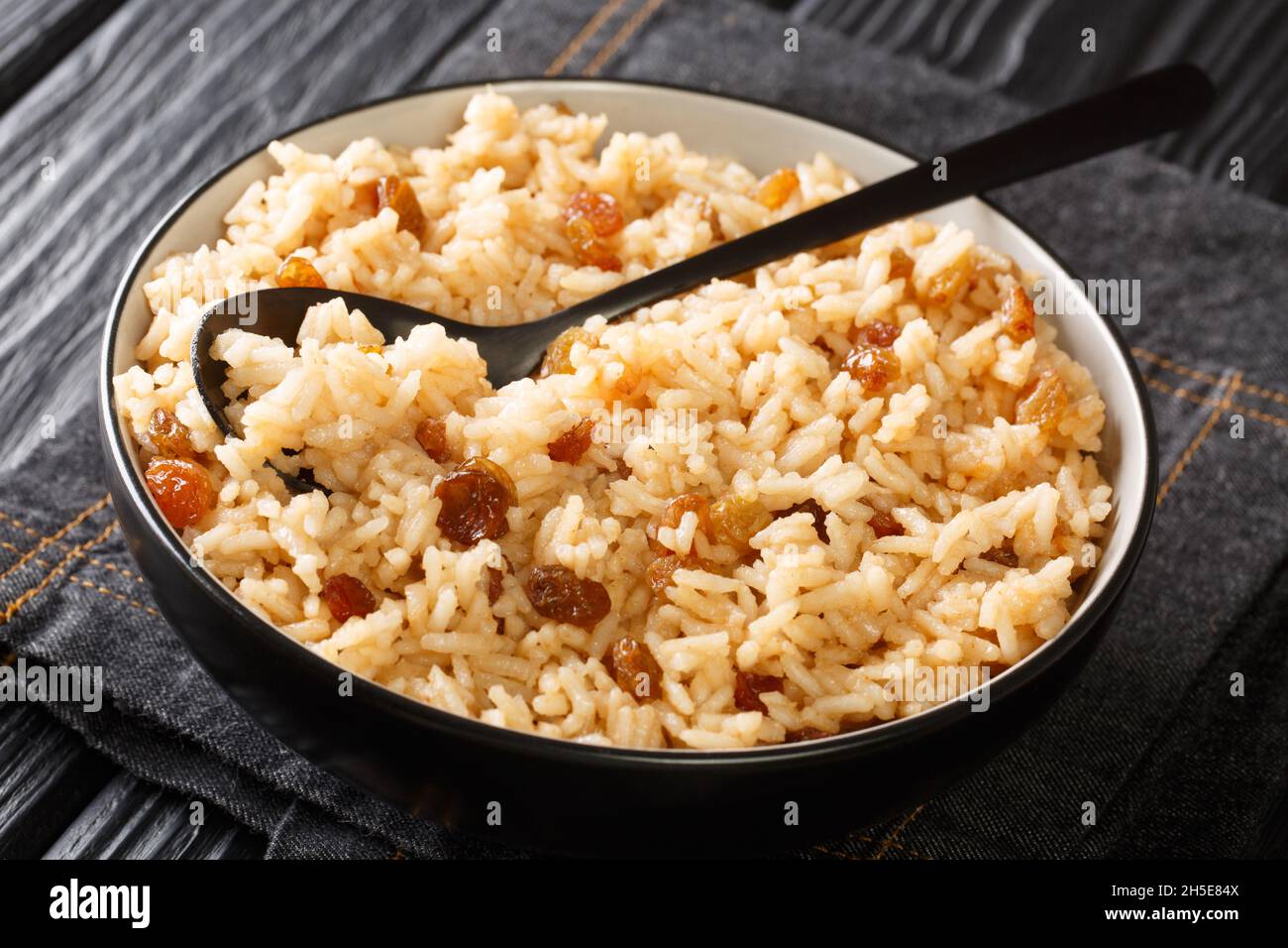 Coconut pilaf rice with raisins close-up in a bowl on the table ...