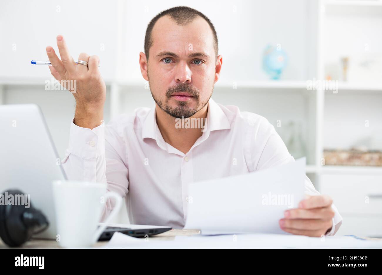 Confused young man at workplace Stock Photo - Alamy