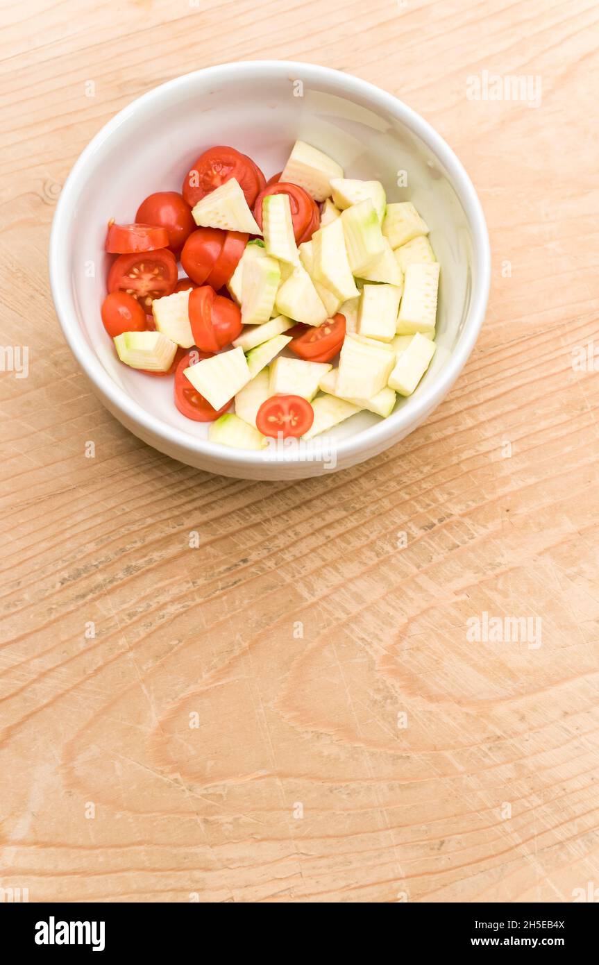 fresh zucchini and datterini tomatoes chunks in a white bowl on a ...