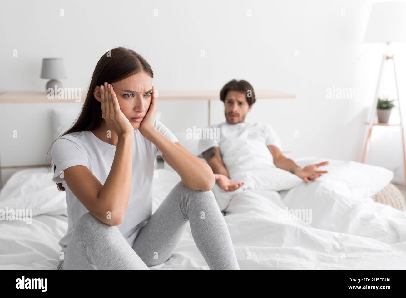 Sad Disgruntled Millennial Caucasian Husband With Stubble Sits On Bed