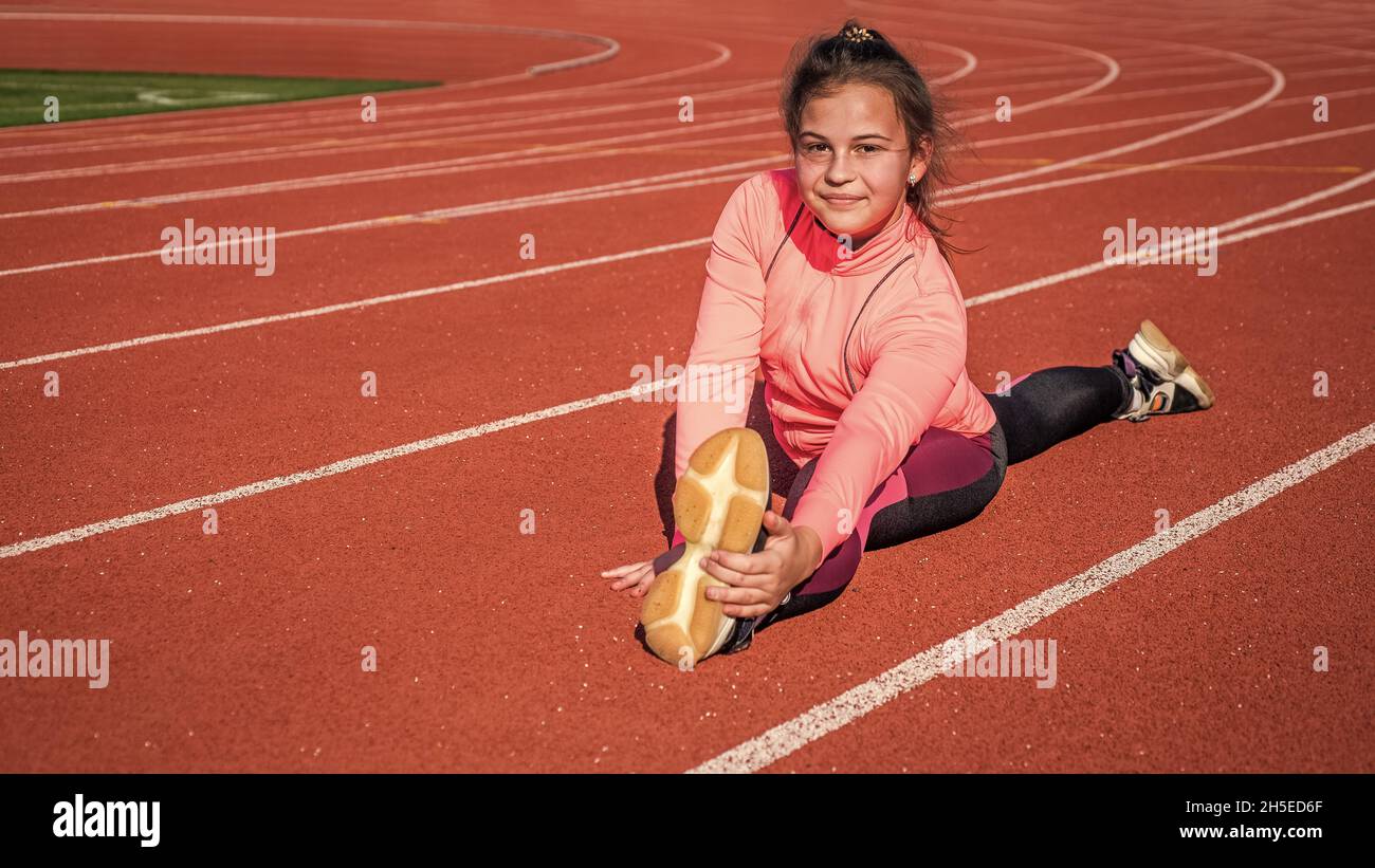 girl kid training sport outside on stadium arena sit in split ...