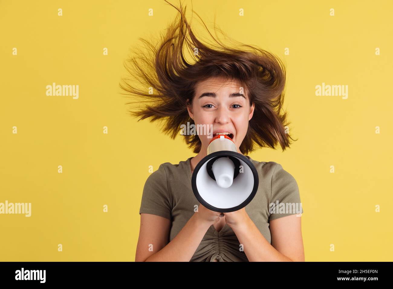 Half-length portrait of young girl, student shouting at megaphone ...