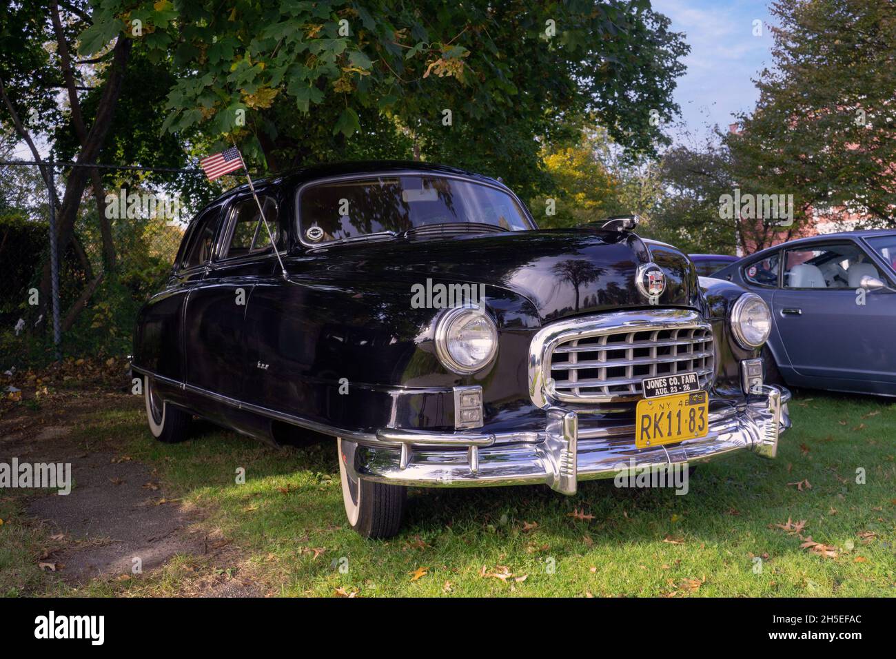 An antique 1949 2 door Nash sedan with an American flag parked outside ...