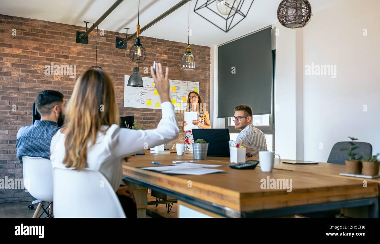 Female manager answering questions in a work meeting Stock Photo - Alamy