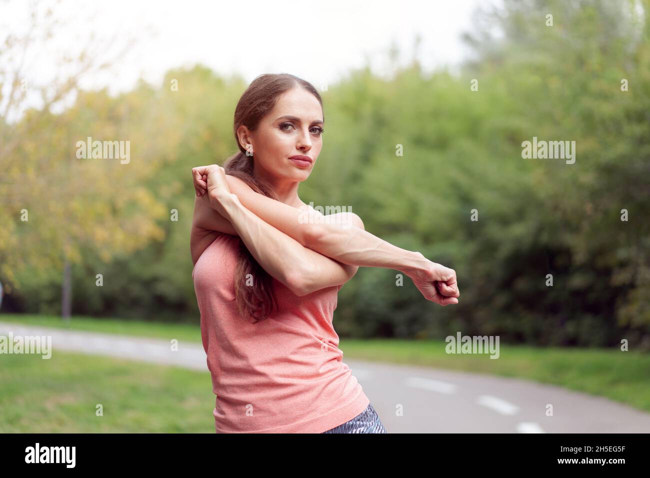 Woman runner stretching arms before running summer park Middle age ...