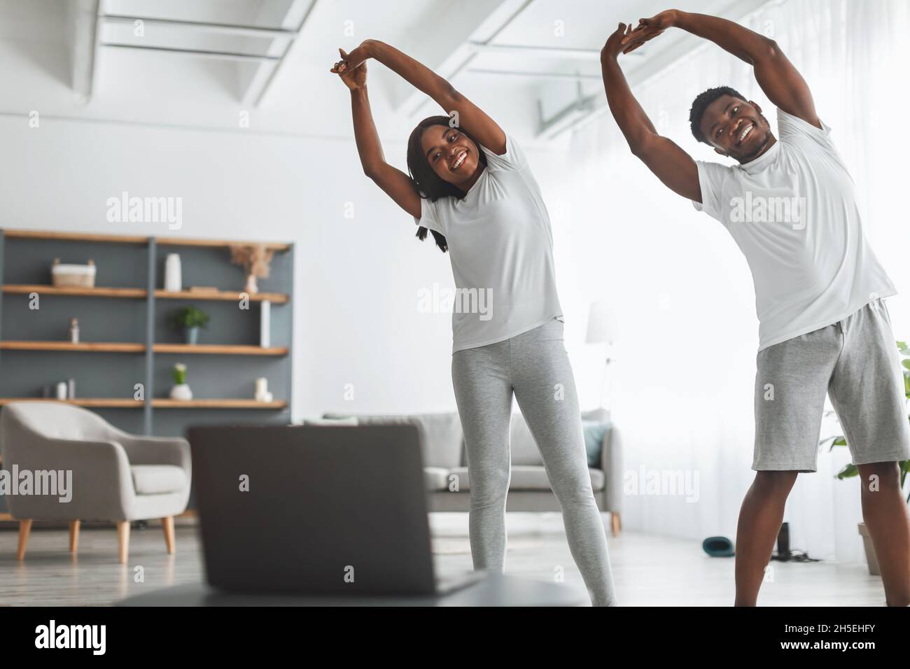 Young black couple doing side bend exercise using pc Stock Photo - Alamy