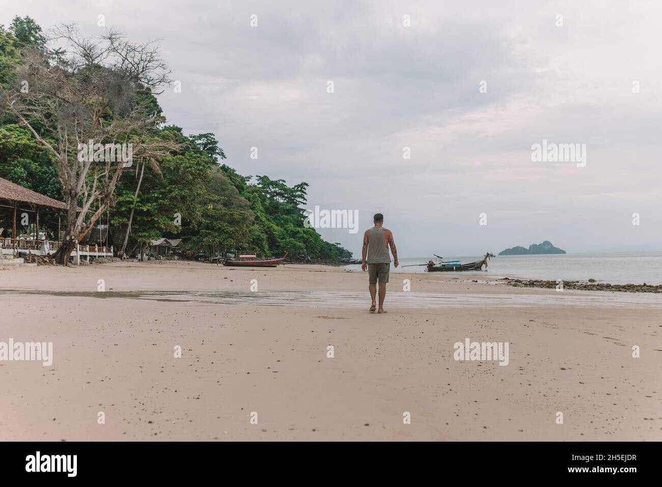 Male walking on a sandy beach on the island on a gloomy day Stock Photo ...