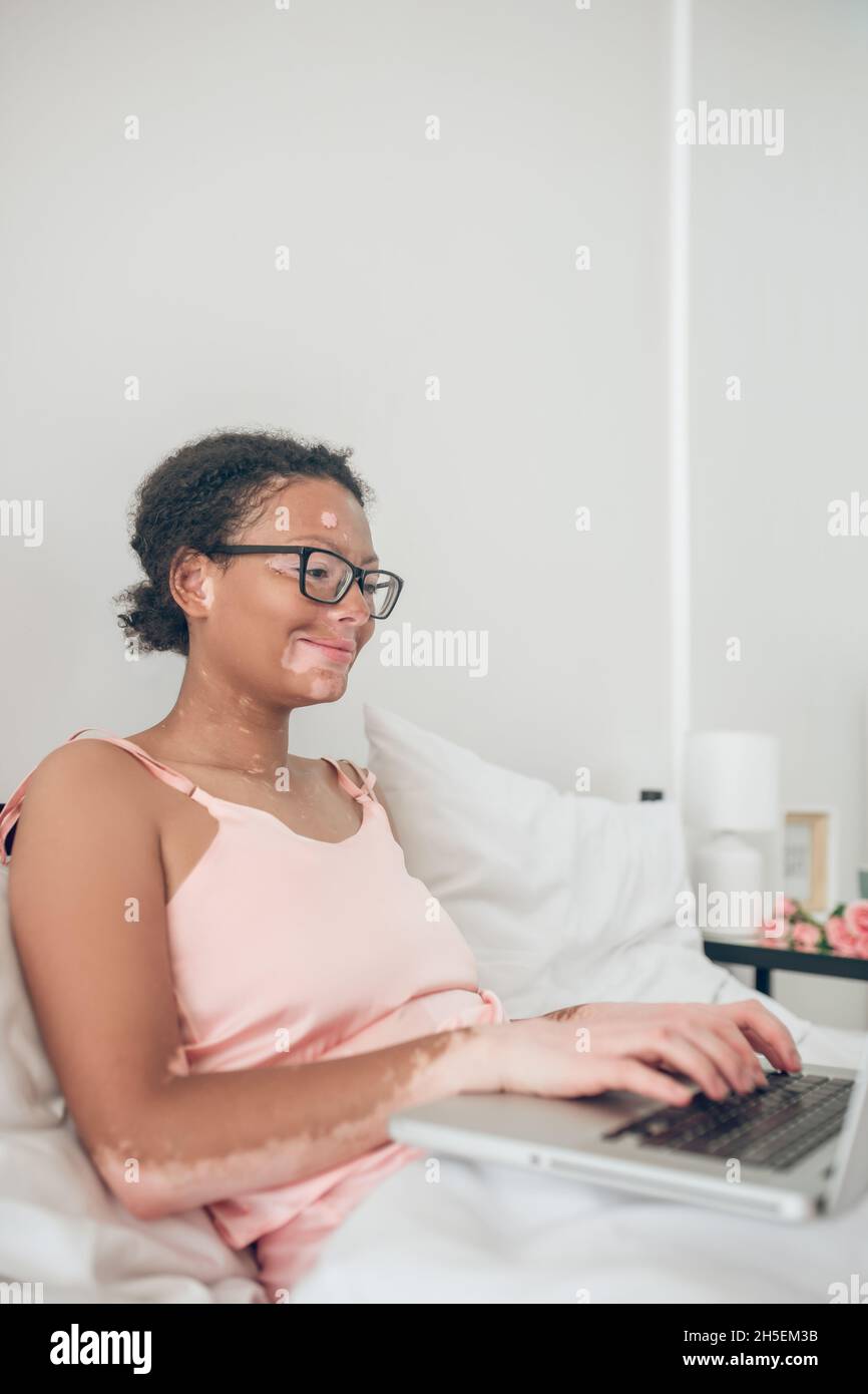 A dark-skinned womant typing on laptop while staying in bed Stock Photo ...