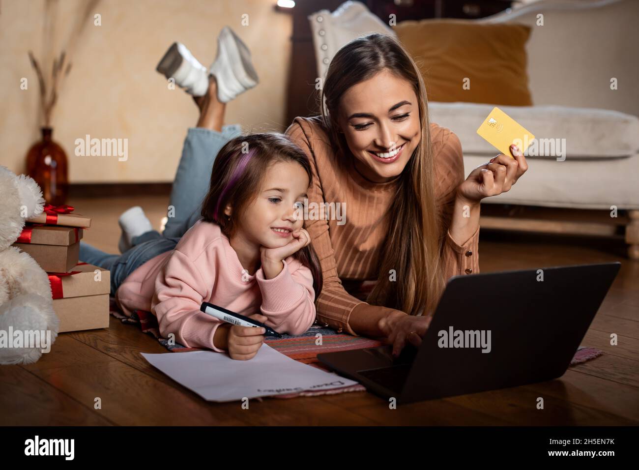 Cute girl writing letter to Santa mom using pc Stock Photo - Alamy
